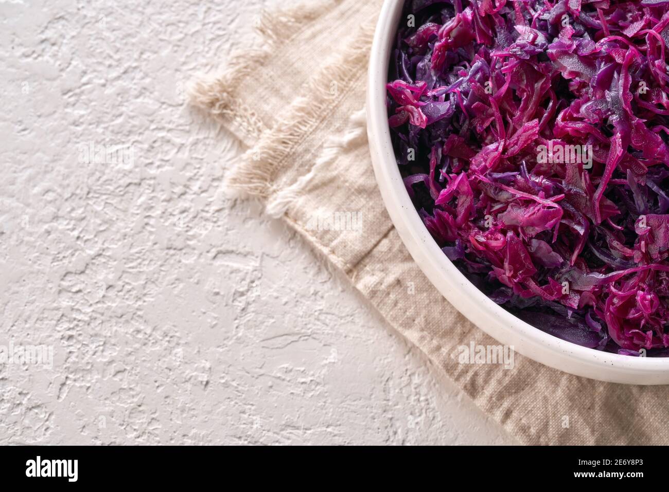 Fermented purple cabbage in a bowl on a white background with copy ...