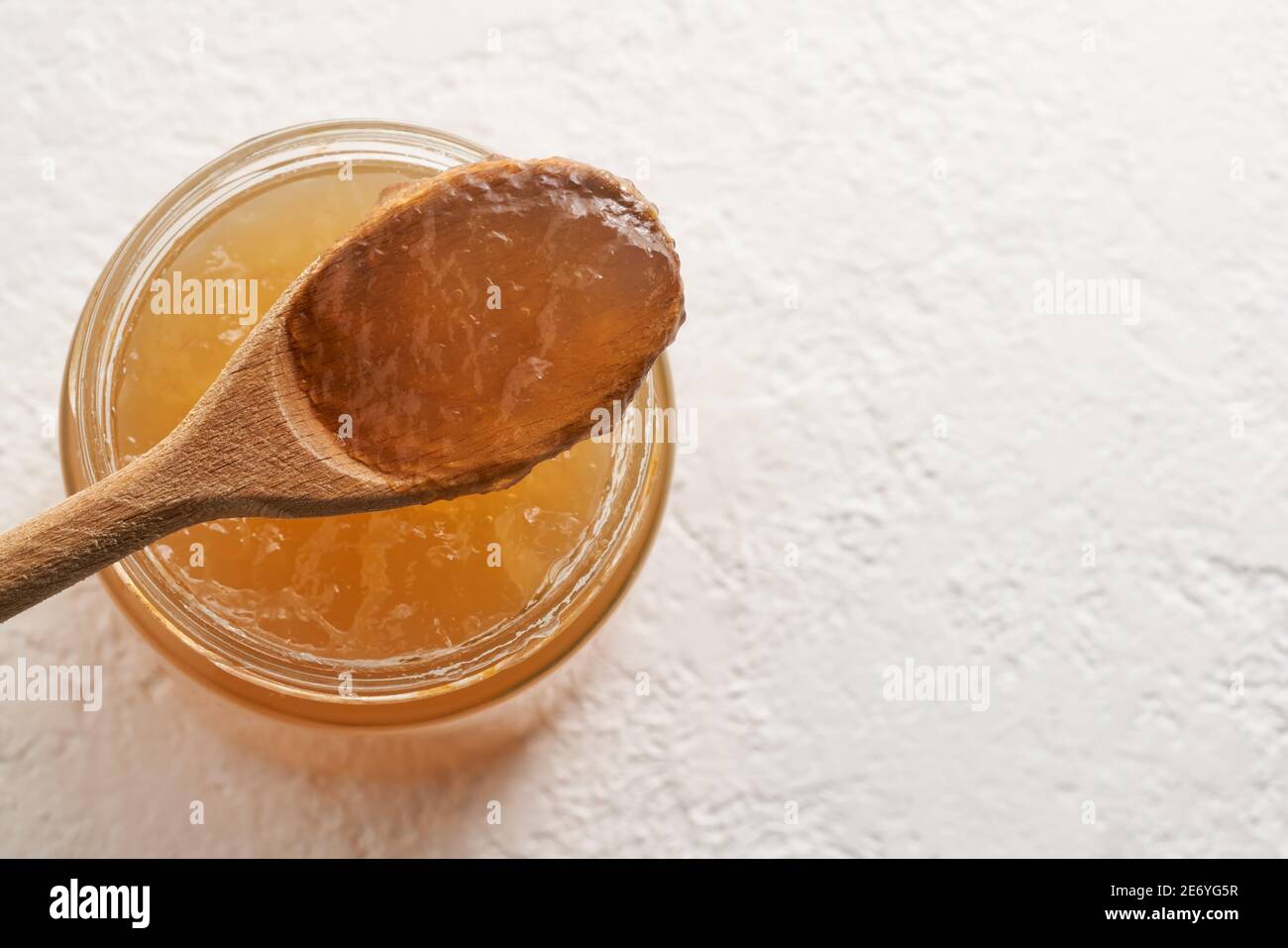 Cooled down congealed beef bone broth in a glass jar and on a spoon, on ...