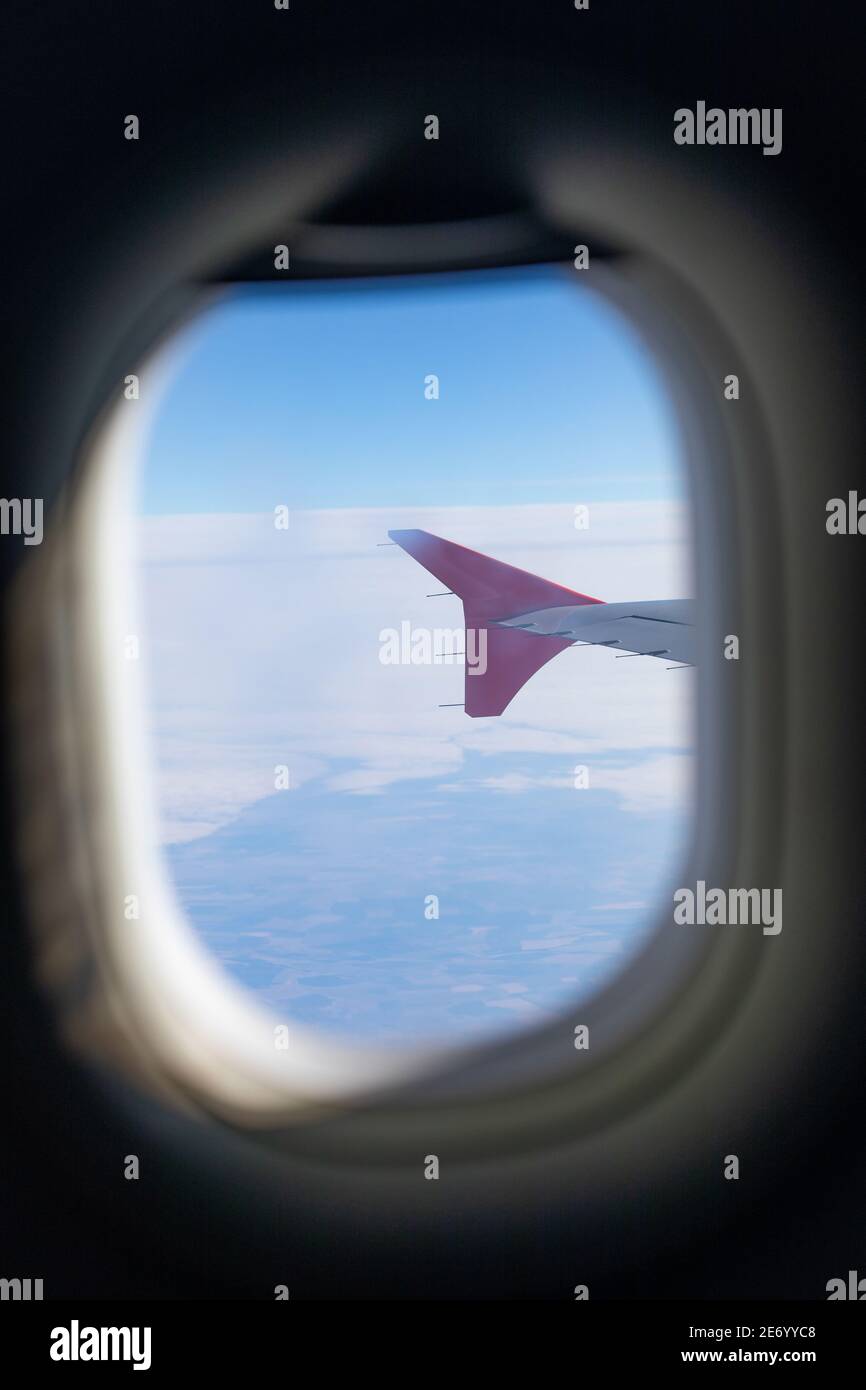 View from dark inside to airplane wing window and sky. Vertical shot ...