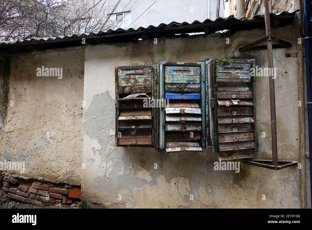 Old rusty mail boxes on the weathered wall. Obsolete broken mailboxes ...