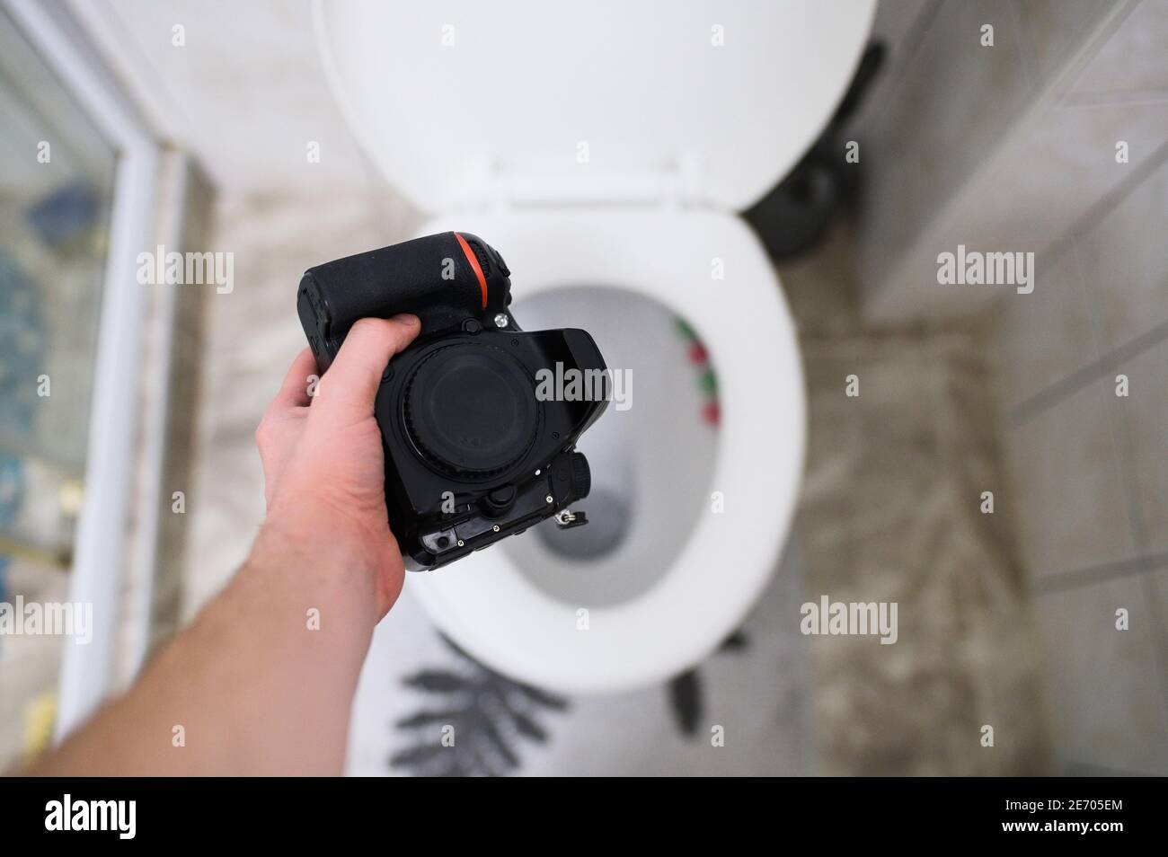 Person holding a camera over the toile Stock Photo - Alamy