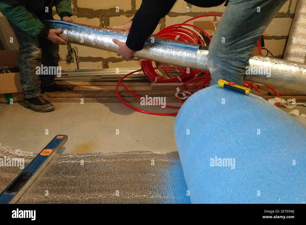 workers wrap galvanized pipe with foil in the newly built house ...
