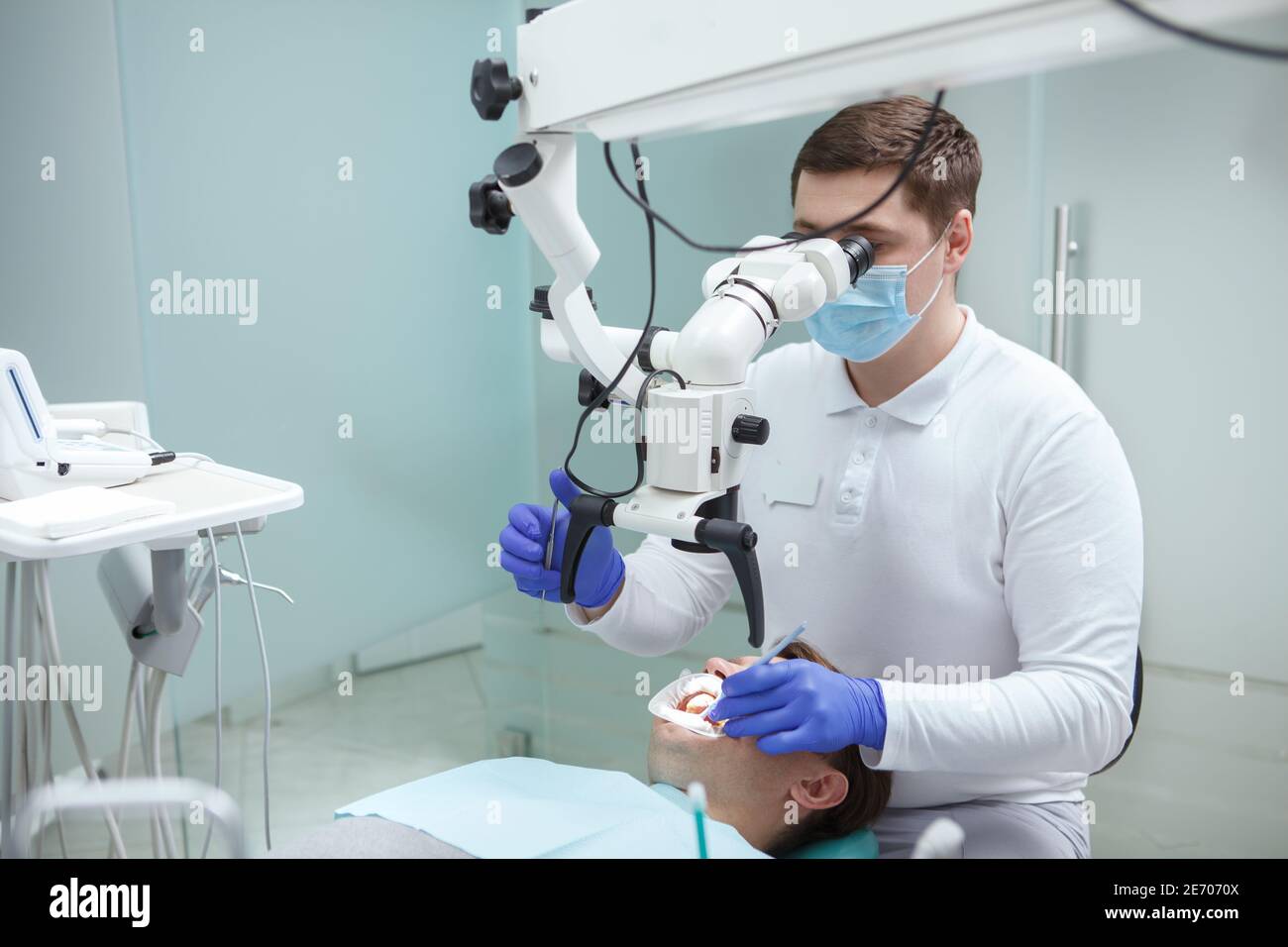 Professional dentist using dental microscope, treating teeth of patient ...