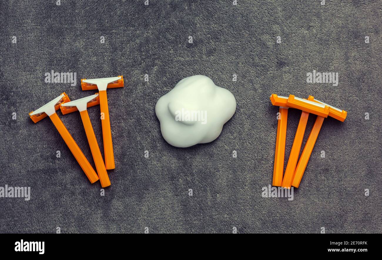 Six disposable orange plastic razors and shaving cream in cloud shape ...