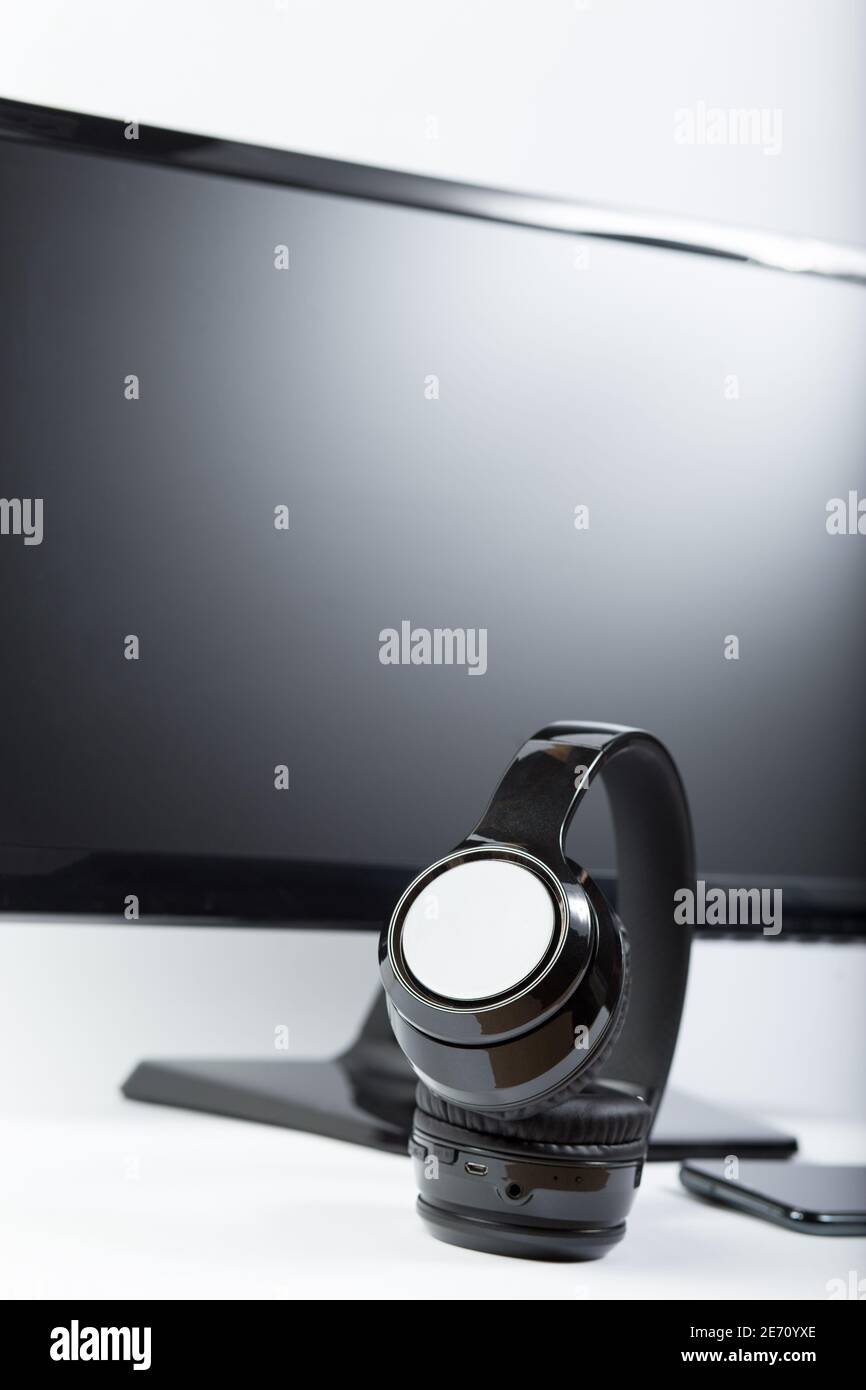 Black wireless jeadphones with smartphone and PC monitor on background ...