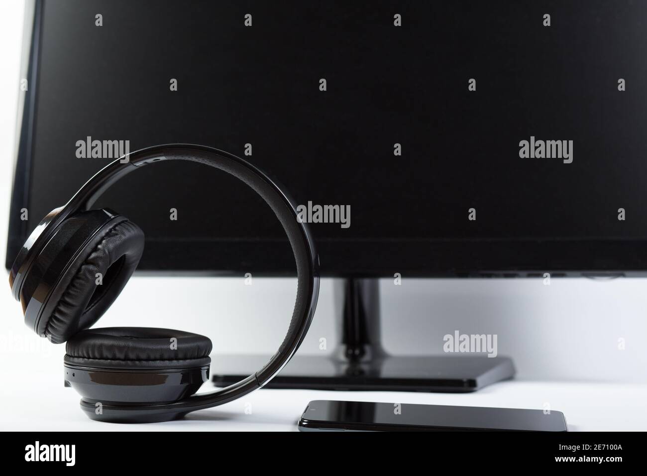 Black wireless headphones and black smartphone with PC monitor on a ...