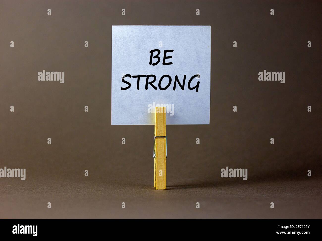 Be strong symbol. Wooden clothespin with white sheet of paper. Words ...