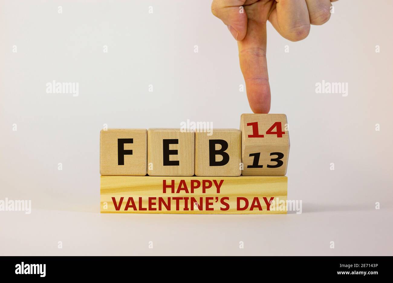 February 14 valentines day symbol. Hand turns a wooden cube. Words 'Feb ...