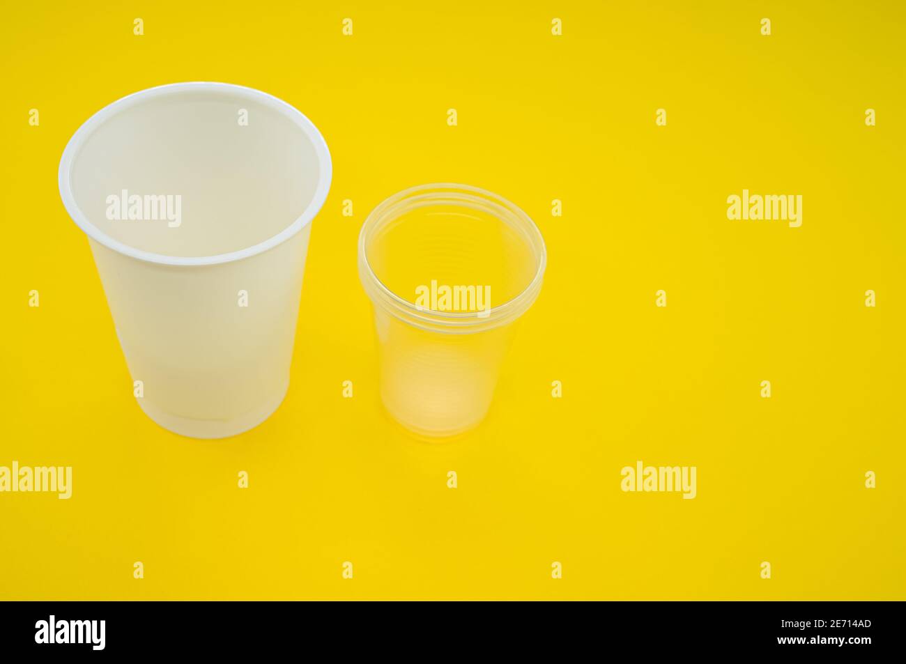 High angle shot of big and small plastic cups on a yellow surface Stock ...