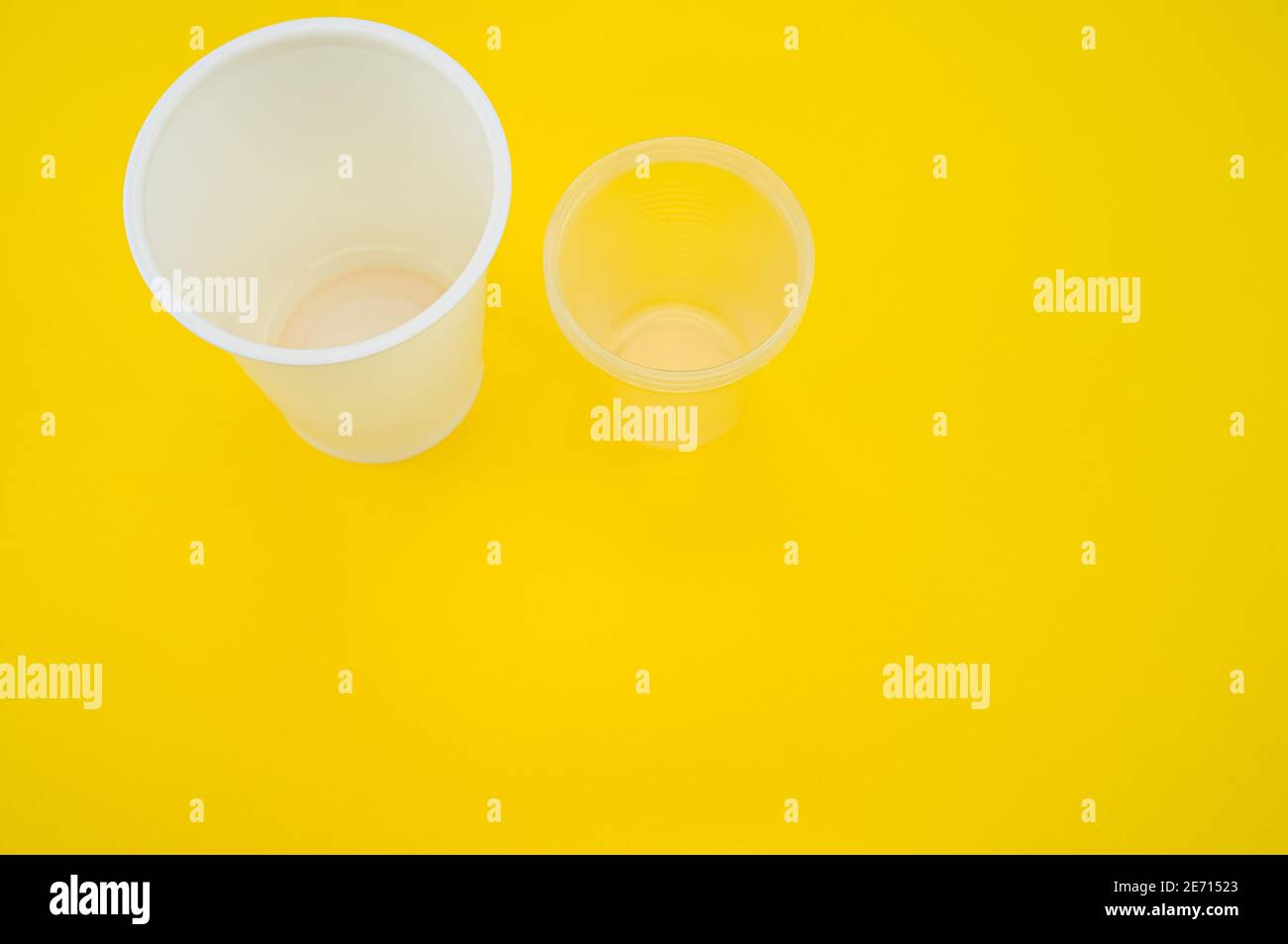 High angle shot of big and small plastic cups on a yellow surface Stock ...