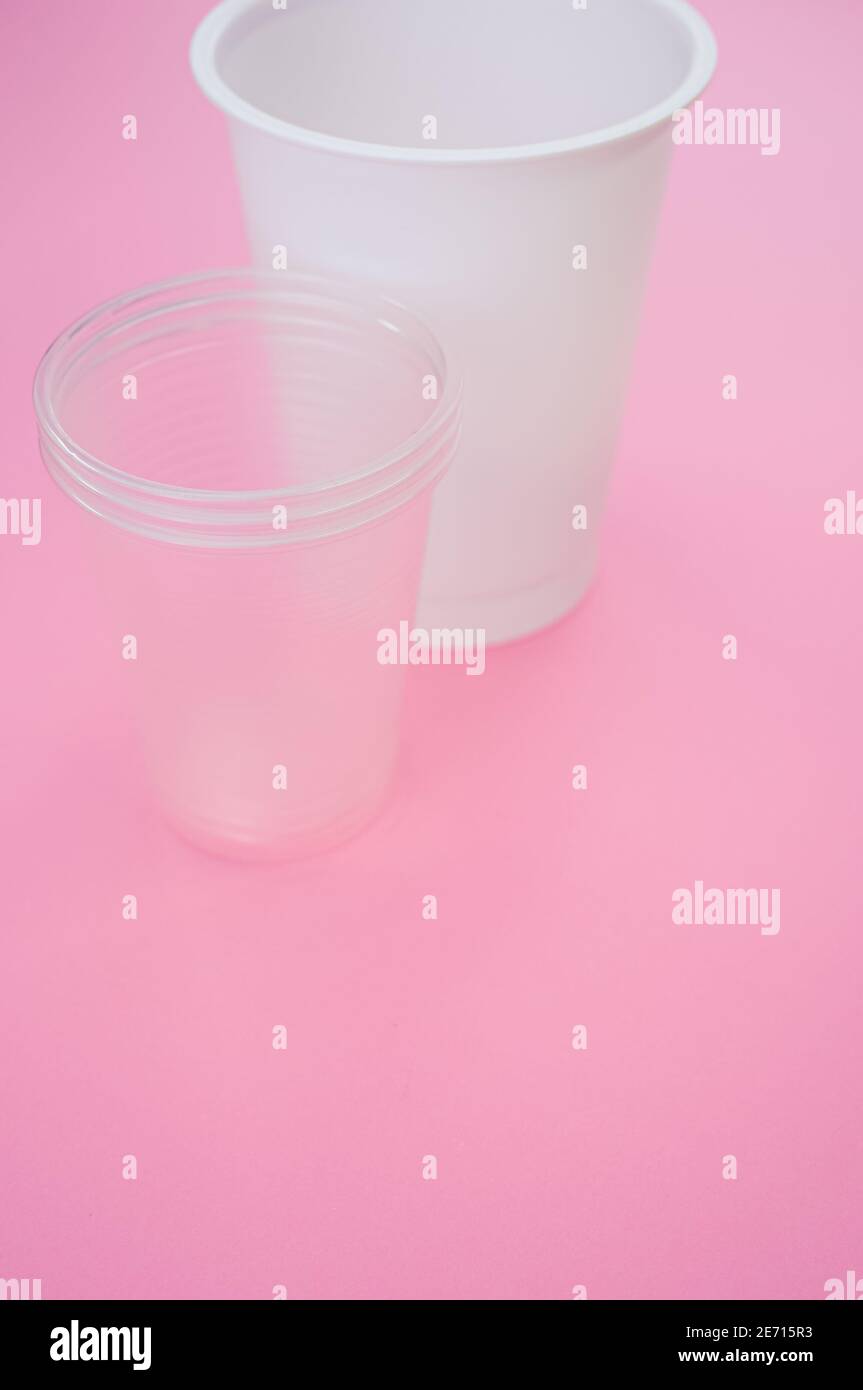 Vertical shot of big and small plastic cups on a pink surface Stock ...