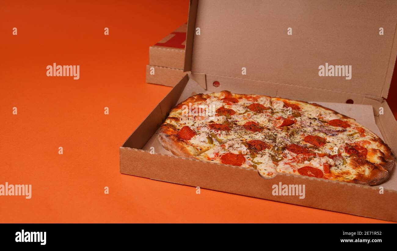 Close up of large pizza in box on orange background. Appetizing pizza ...