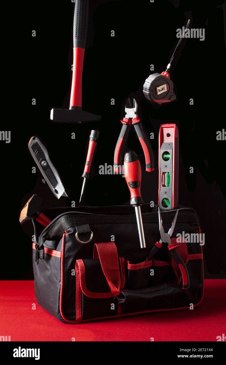 Tools falling into a tool bag on a black background Stock Photo - Alamy