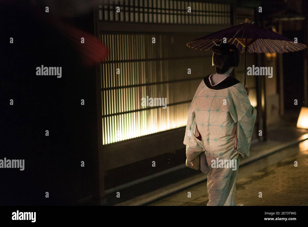 Geisha walking with umbrella enroute to a job on a rainy night in Kyoto ...