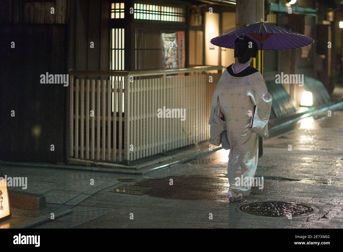 Geisha walking with umbrella enroute to a job on a rainy night in Kyoto ...