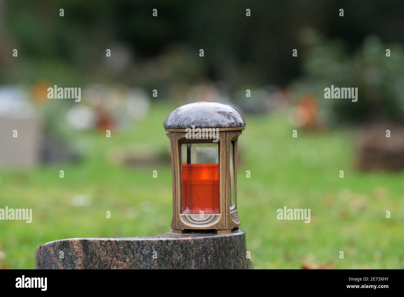 metal grave lantern on a marble pedestal in front of graves in blurred ...