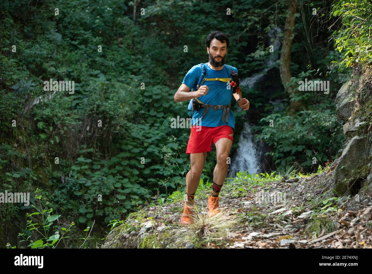 One man running down on a trail with a waterfal Stock Photo - Alamy