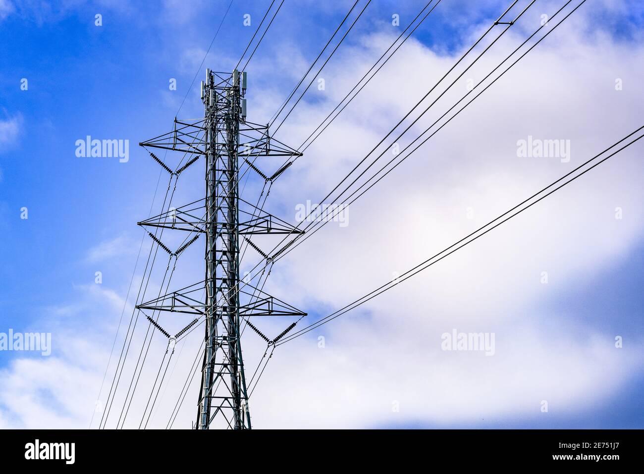 High voltage electricity tower; white clouds and blue sky background ...