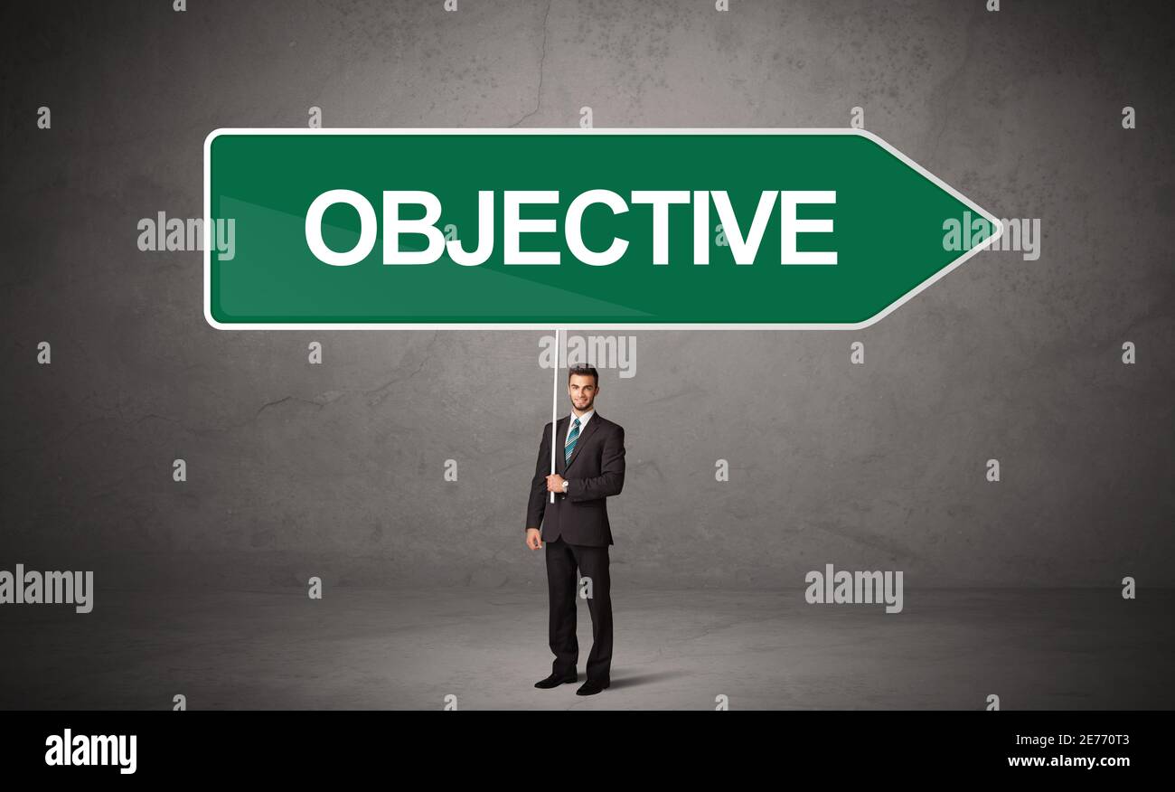 Young business person in casual holding road sign with OBJECTIVE ...