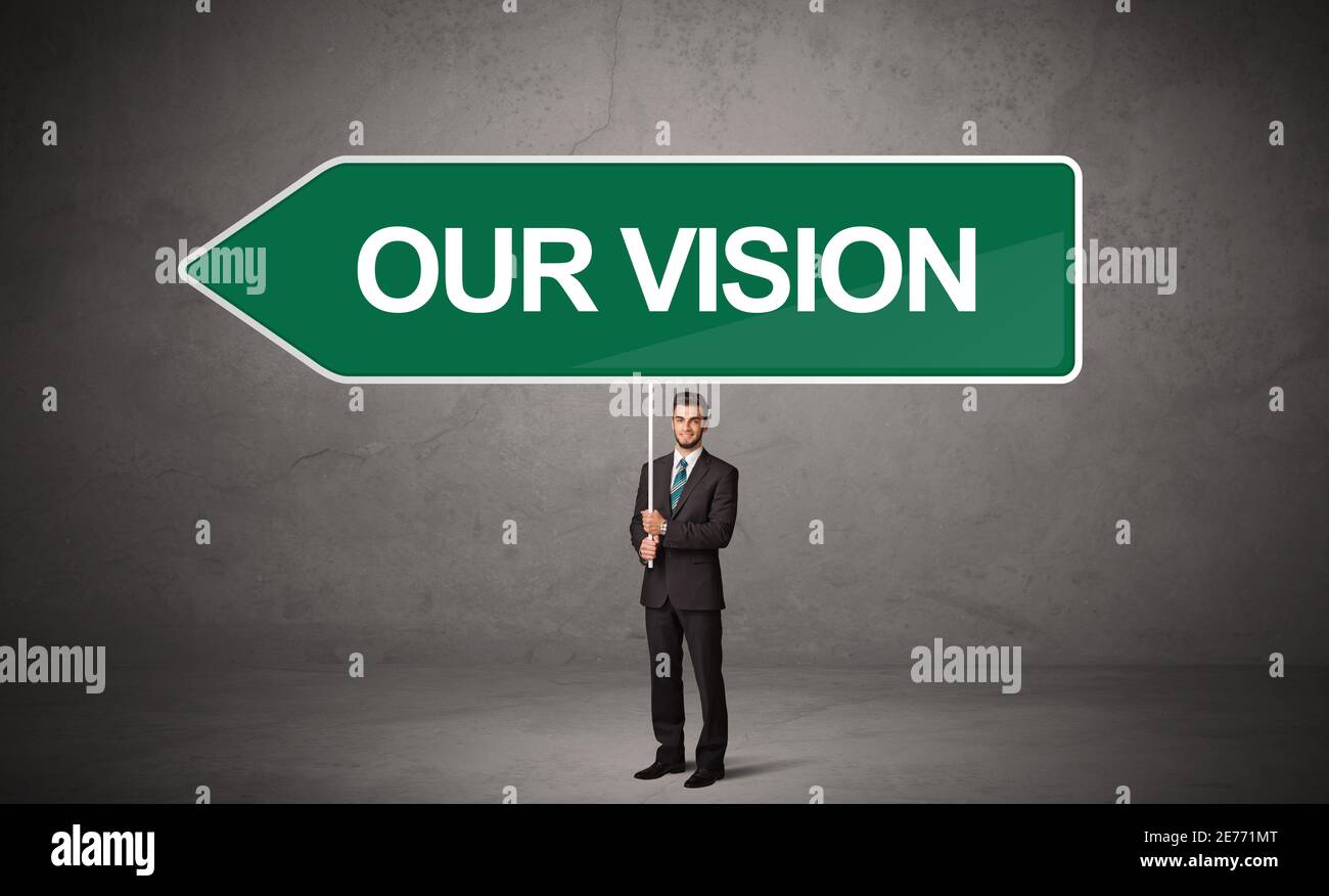 Young business person in casual holding road sign with OUR VISION ...