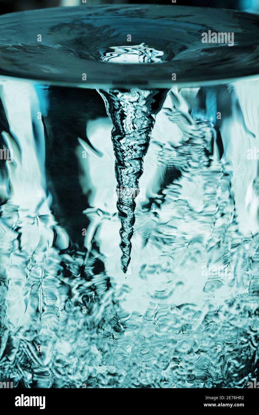 Vortex of water in glass tube, tornado, storm in blue water glass with ...