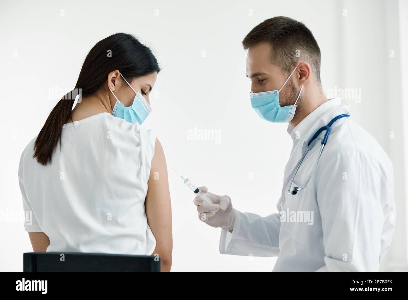 doctor inject vaccine into woman shoulder and medical mask light ...