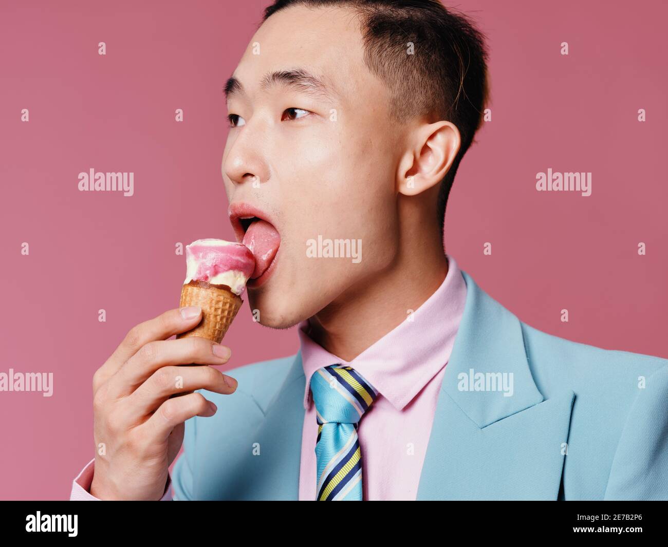 Asian man eating ice cream on pink background cropped view Stock Photo ...