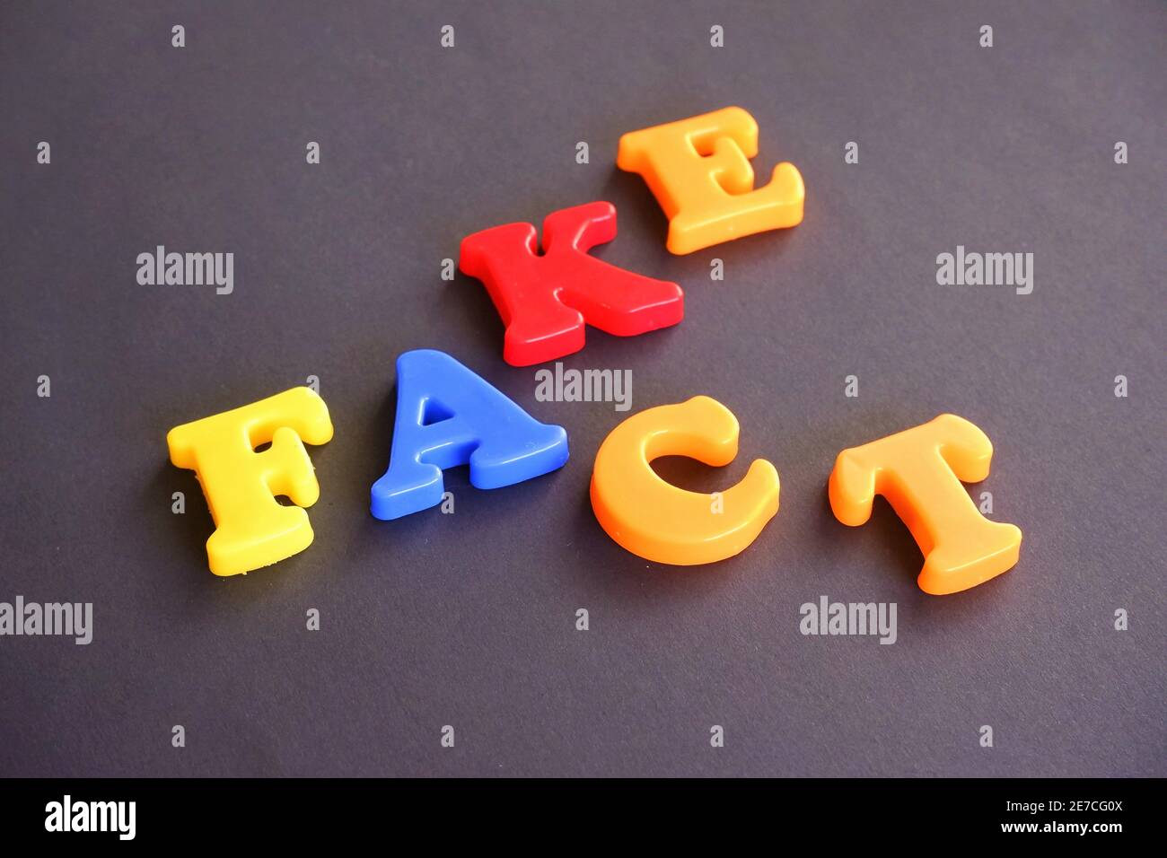 Fake and fact words in colorful plastic magnetic letters on a dark grey ...