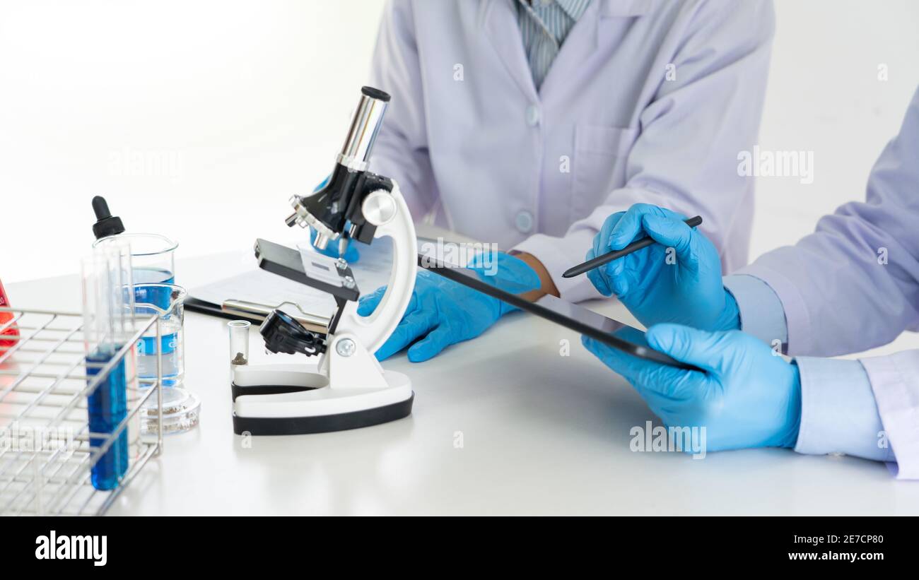 Attractive young scientist team in lab coat and safety goggles working ...