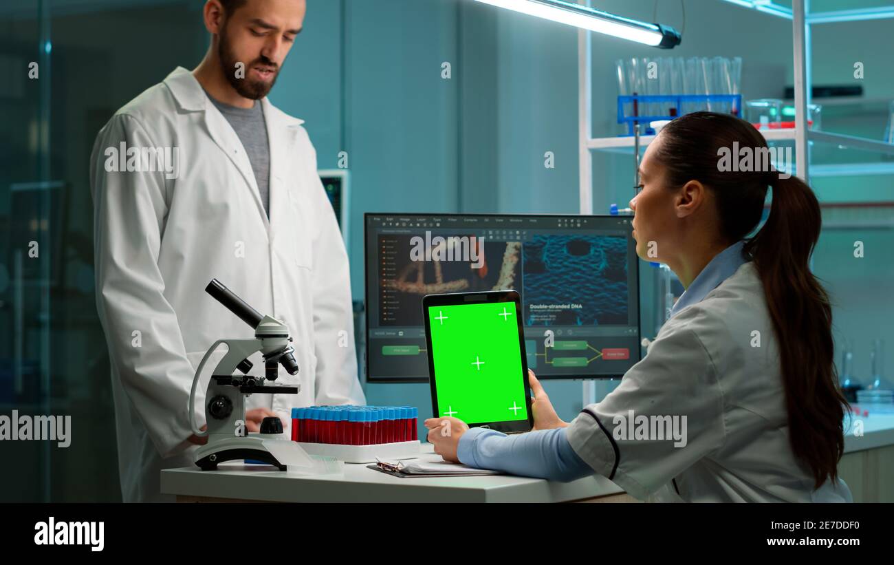 Female chemist scientist using green mock-up screen tablet sitting at ...