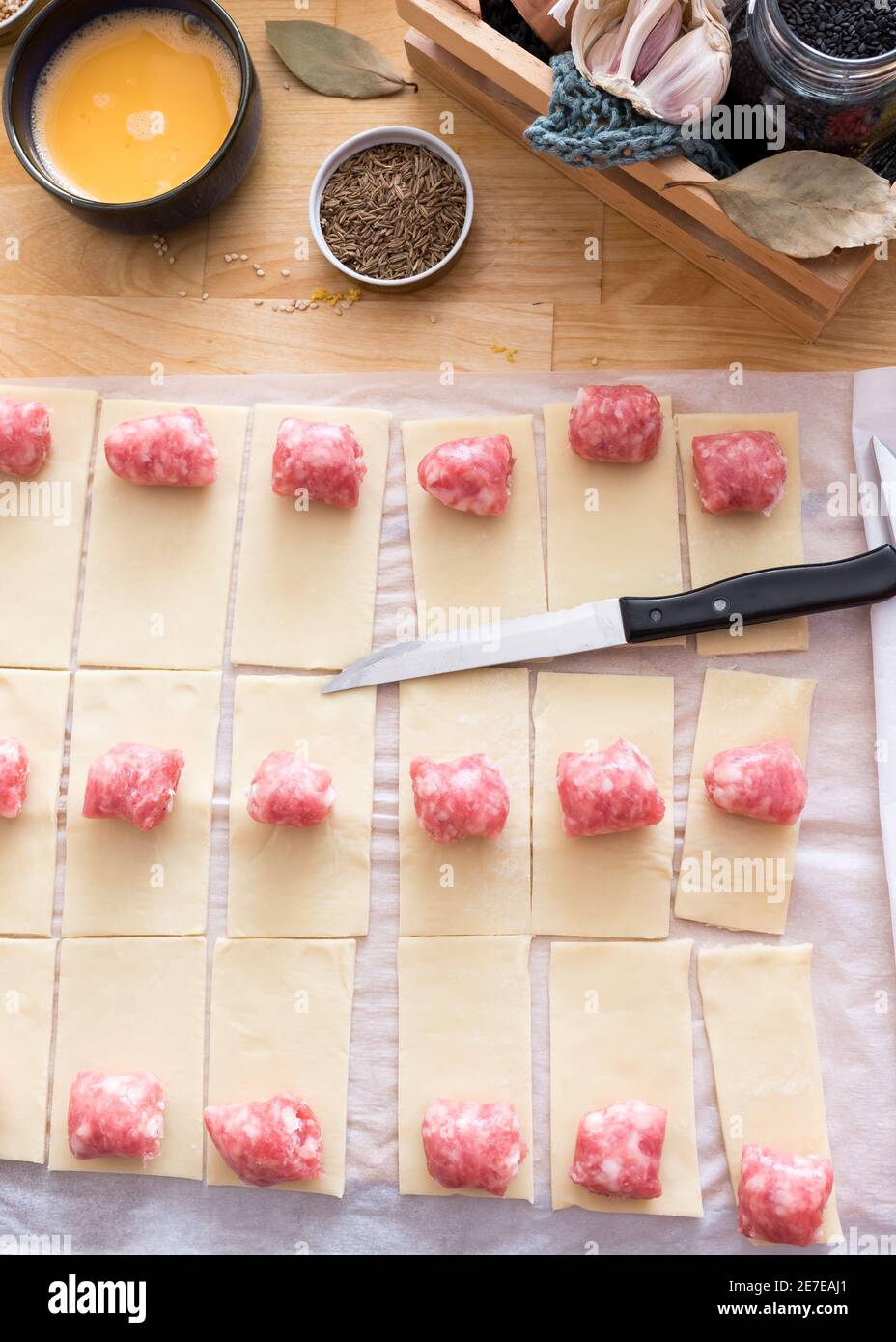 Pork raw meat slices on just cut puff pastry rectangles ready to be ...