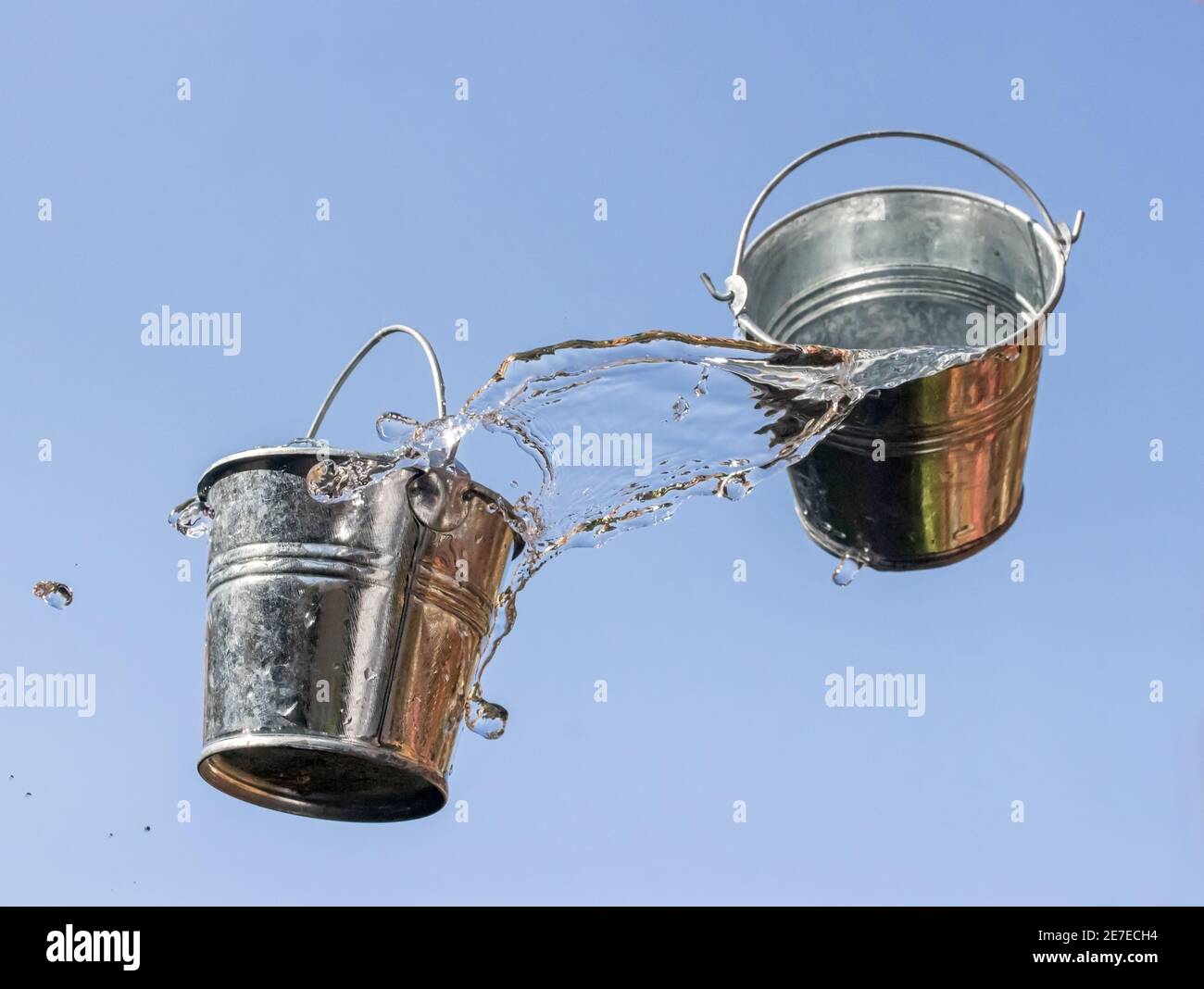 A pouring water from falling bucket to bucket, on a background of blue ...