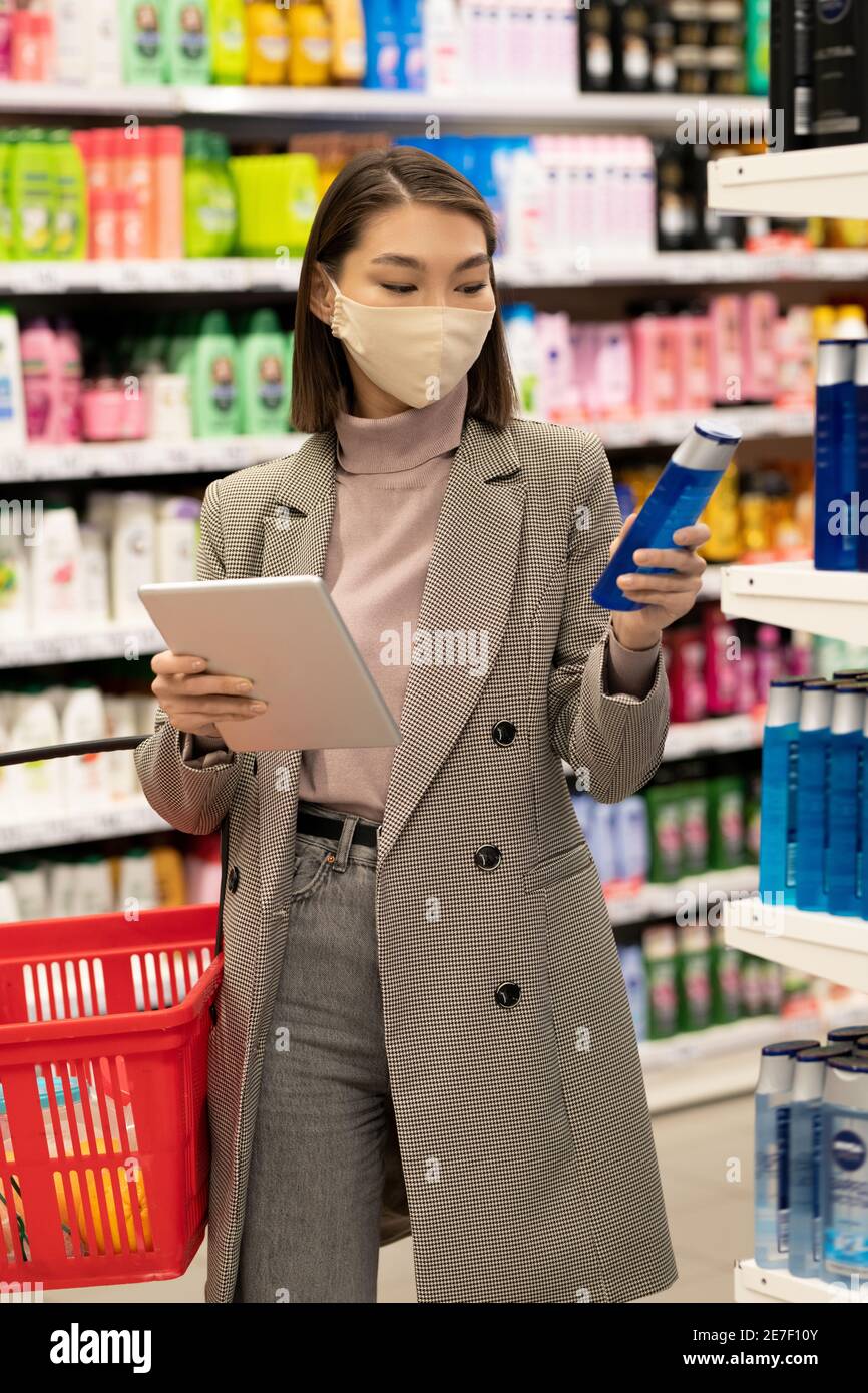 Young Asian female consumer with red basket and tablet standing by ...