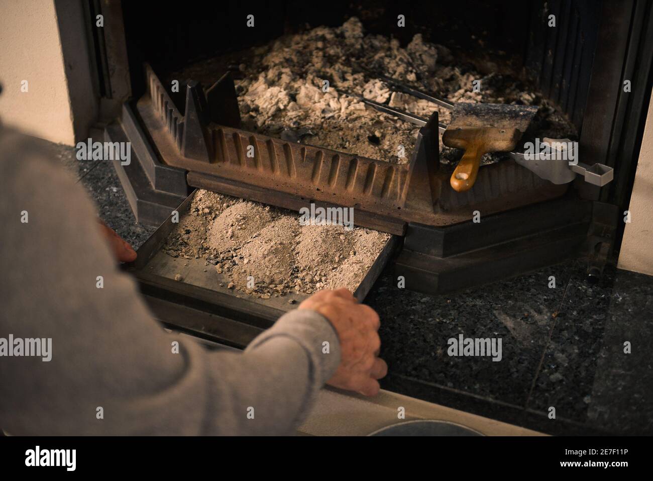 A man cleaning ashes in the fireplace tray Stock Photo - Alamy