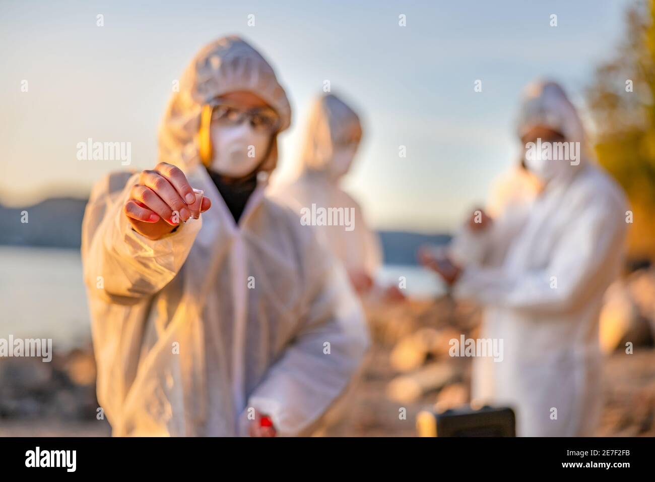 Scientist in white protective suit holding water sample at beach Stock ...