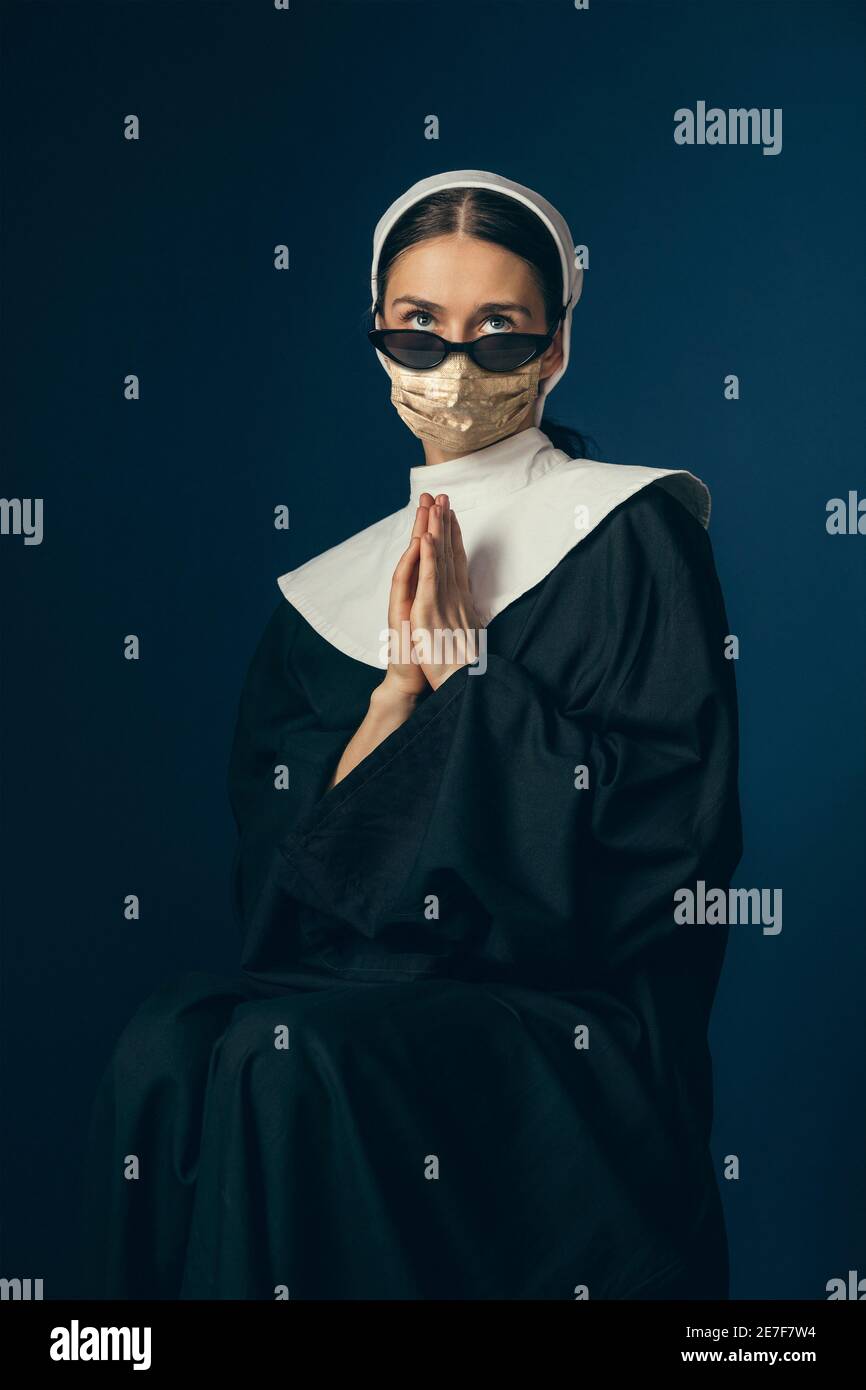 Medieval young woman as a nun in vintage clothing and golden face mask ...
