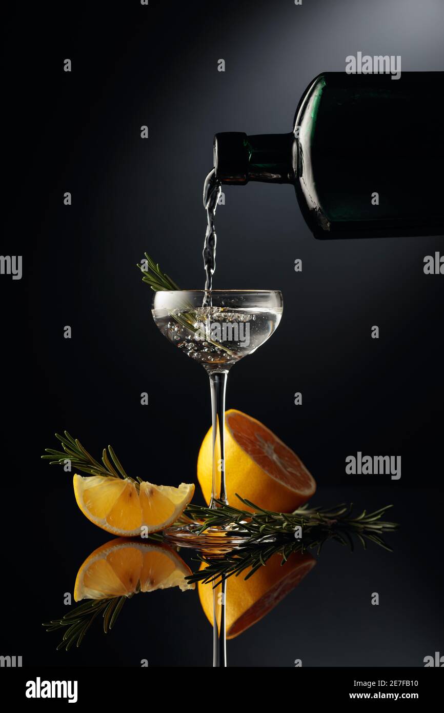 Gin is poured in a small glass from an antique bottle of dark glass. A ...