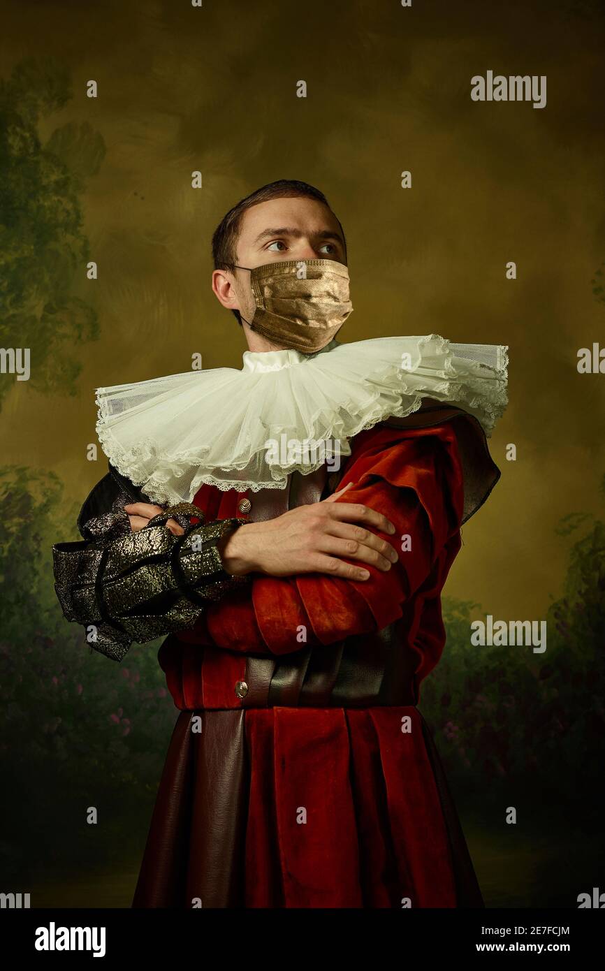 Portrait of medieval young man in vintage clothing and golden face mask ...