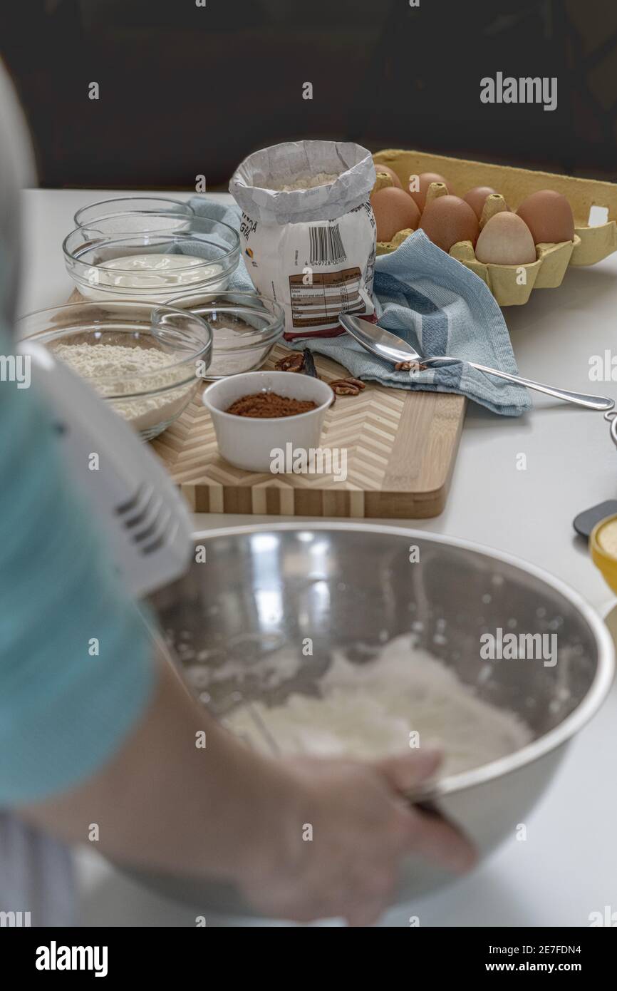 Vertical shot of a person baking a cake with butter, cocoa powd, flour ...