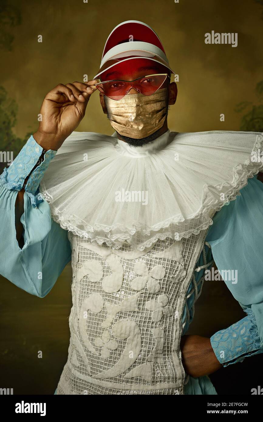 Portrait of medieval young man in vintage clothing, golden face mask ...