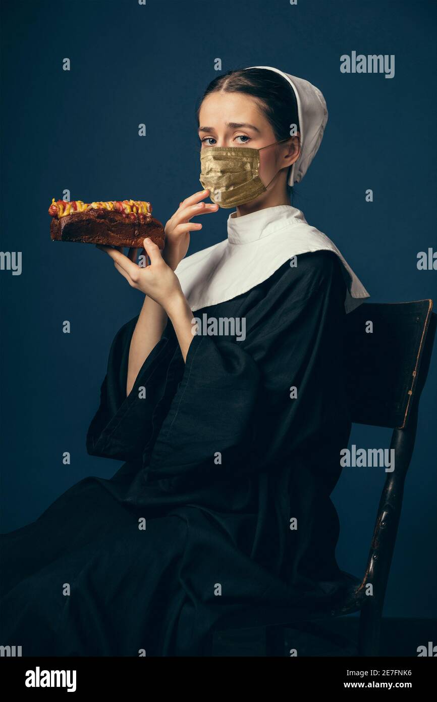 Medieval young woman as a nun in vintage clothing and golden face mask ...