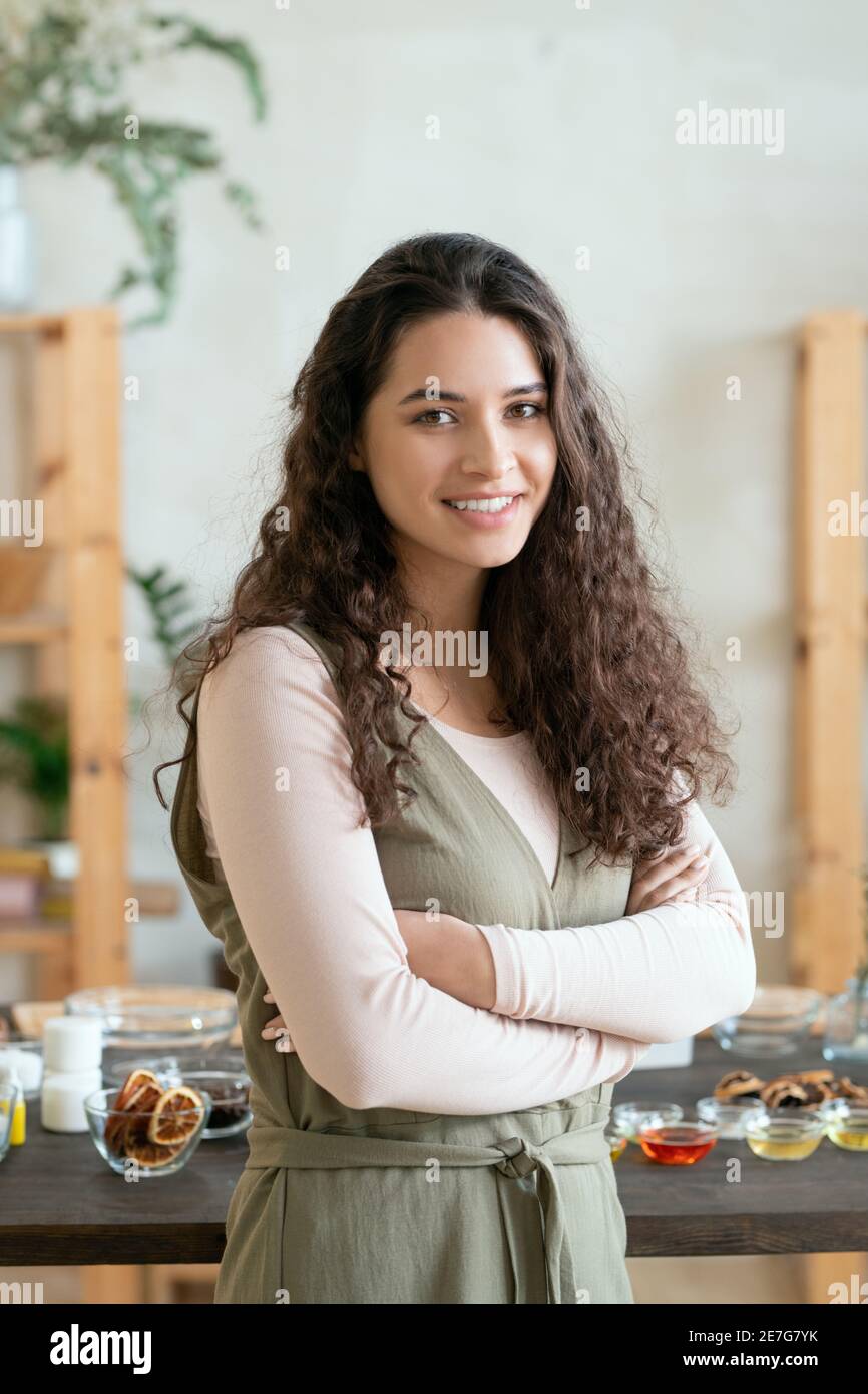 Young smiling brunette woman crossing arms by chest while standing ...