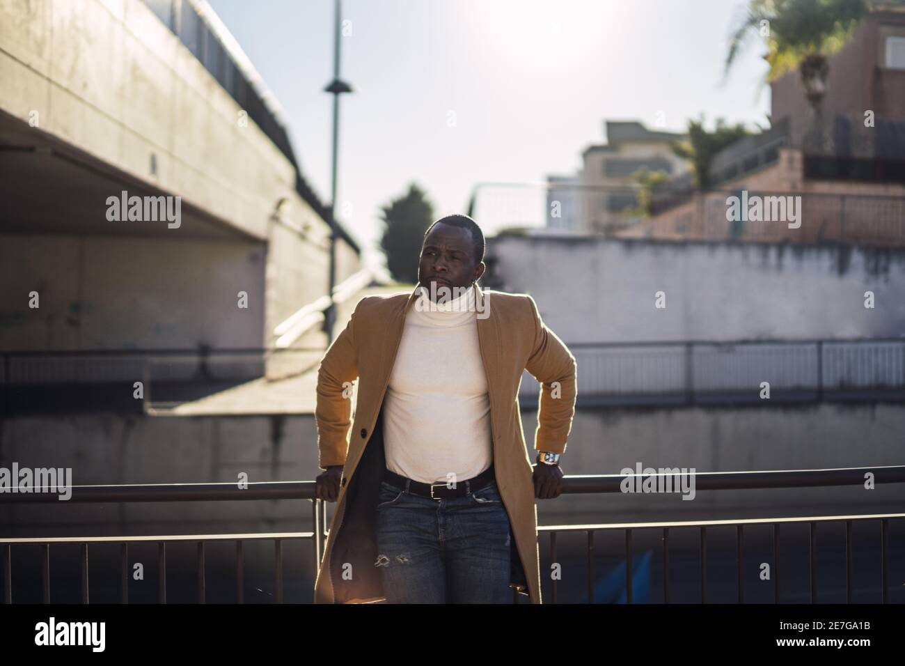 Stylish handsome African male in a coat leaned on railing posing for ...