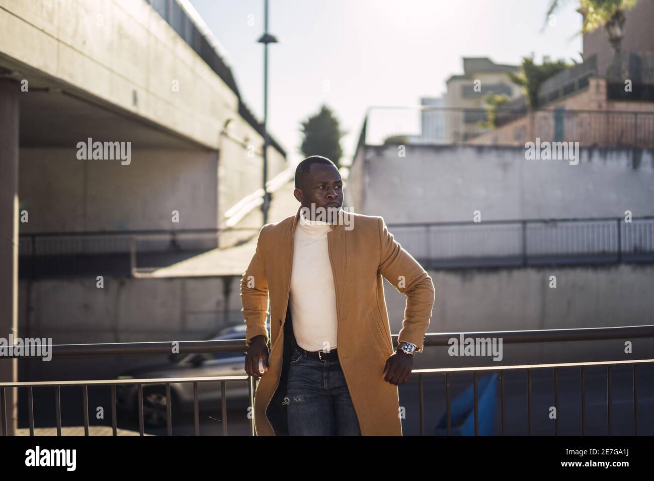Stylish handsome African male in a coat leaned on railing posing for ...