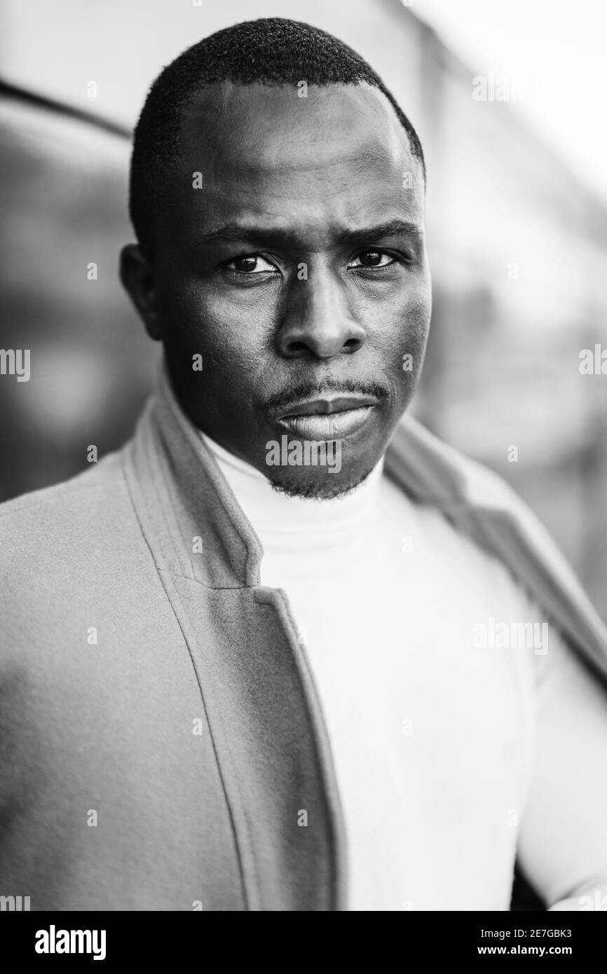 Grayscale shot of a stylish handsome African male in a coat posing for ...