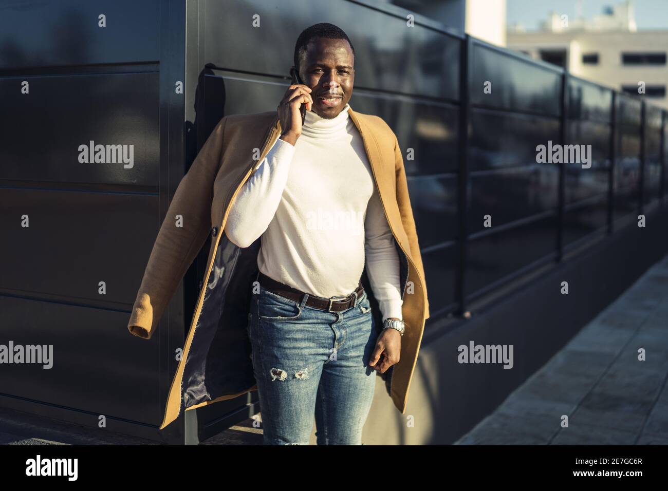 Shallow focus shot of a stylish handsome smiling African male in a coat ...
