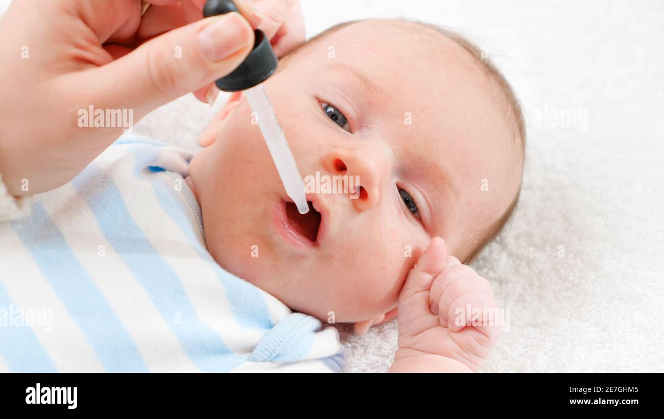 Closeup of giving vaccine to newborn baby boy from eyedropper or ...