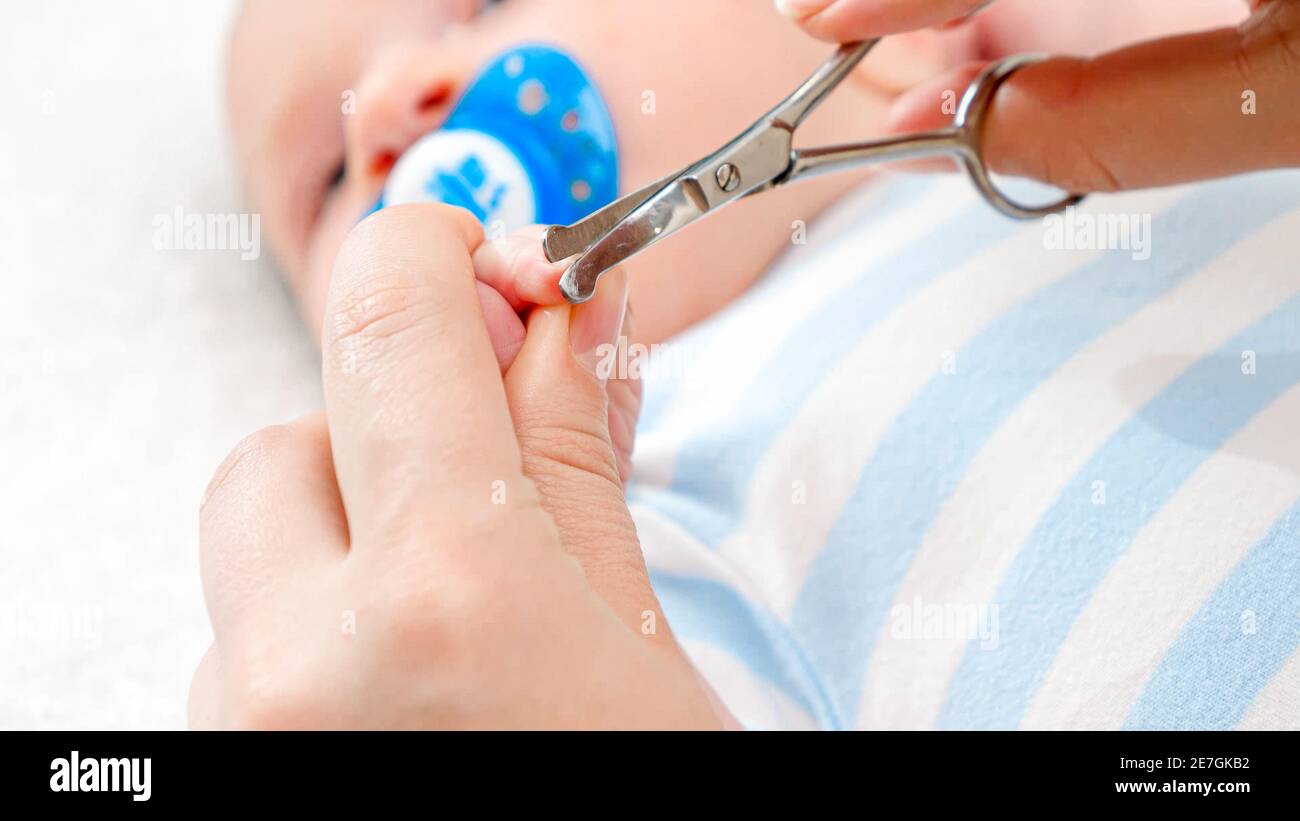 Closeup of cutting newborn baby finger nails with special scissors ...