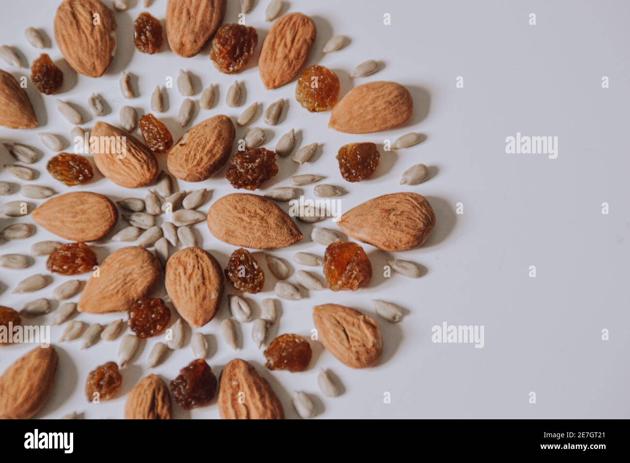 Overhead shot of types of nuts in a floral shape on a white backgrou ...