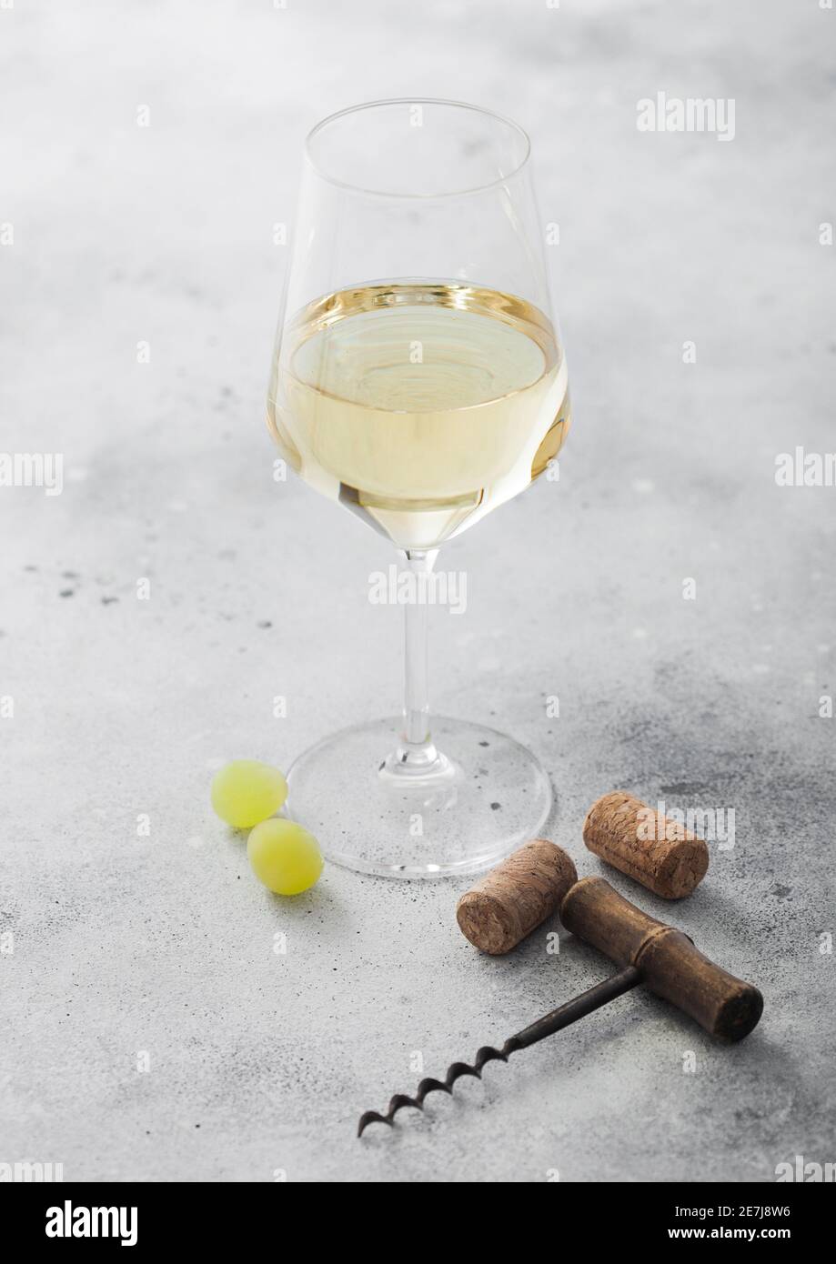 Glass of white homemade wine with corks, corkscrew and grapes on light ...
